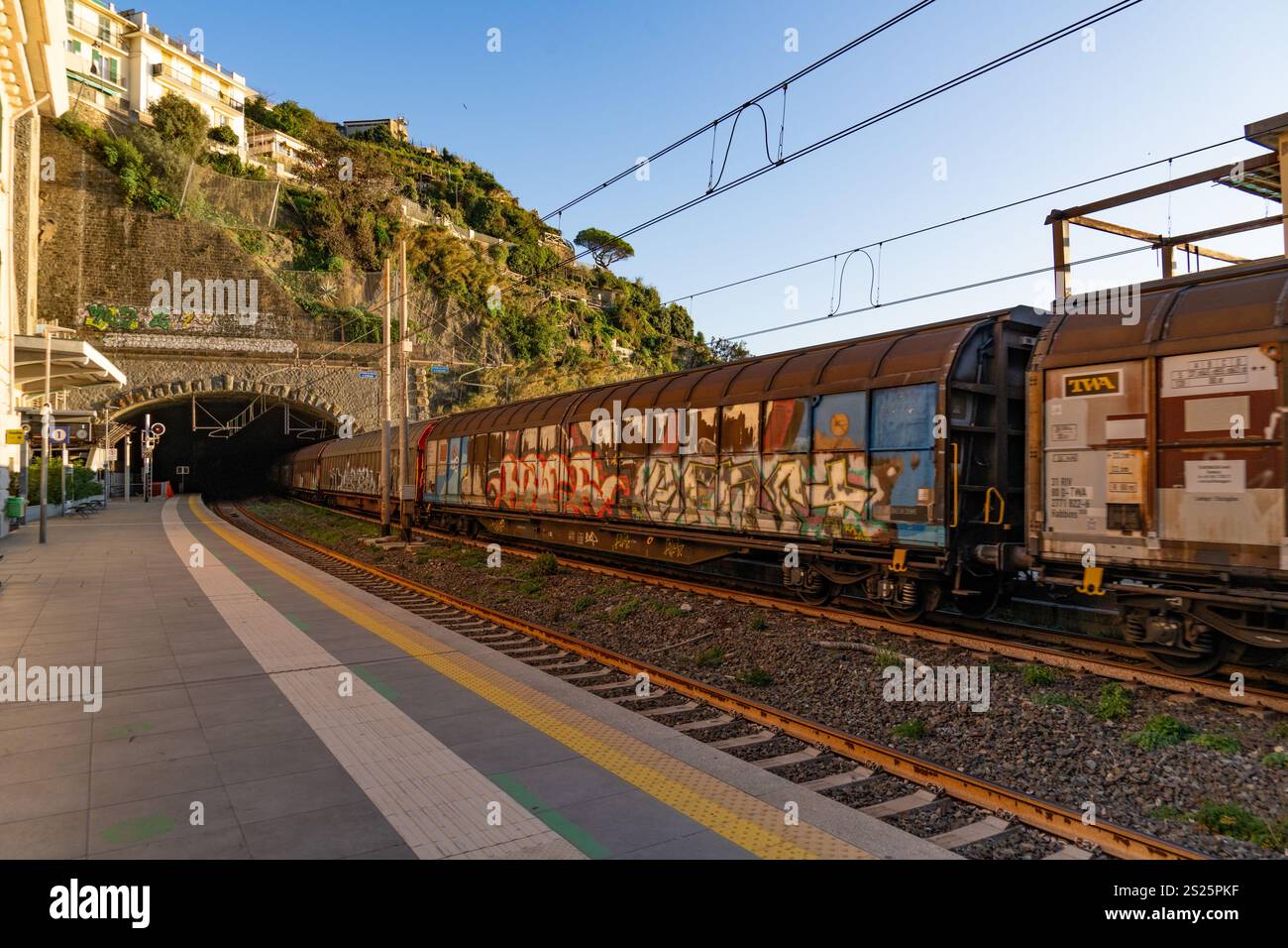 A freight train enters a tunnel by the train station for Riomaggiore ...