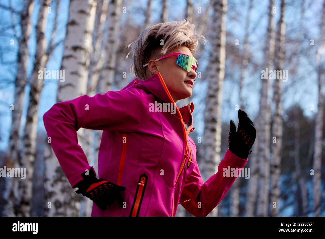 Athletic runner woman in pink jacket and yellow jogging pants running ...