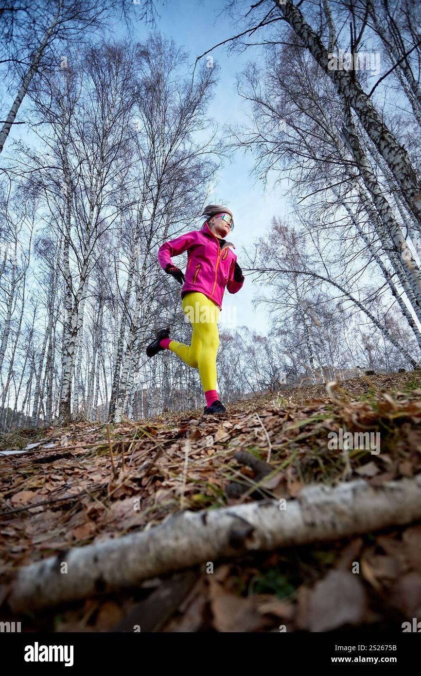 Athletic runner woman in pink jacket and yellow jogging pants running ...