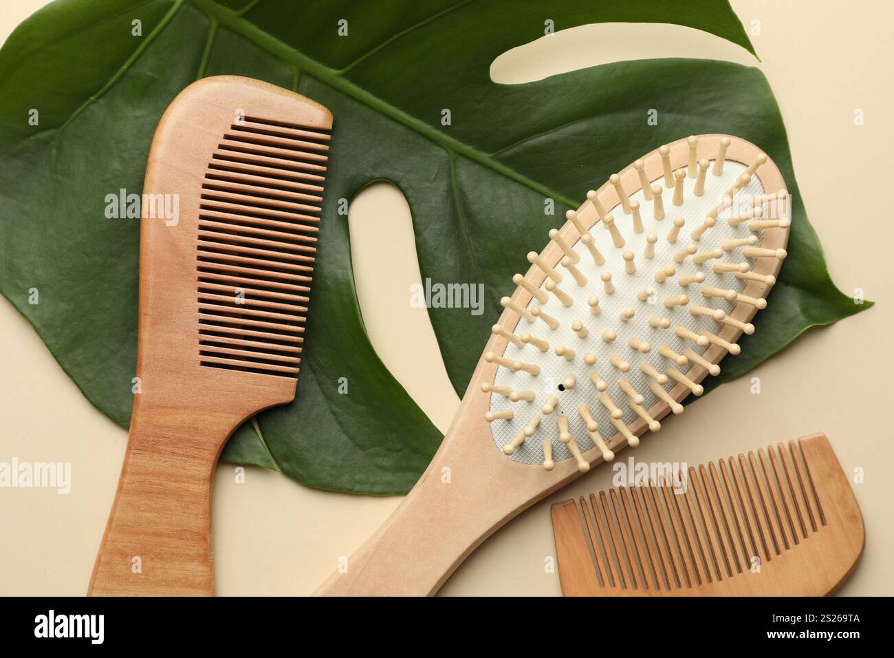 Wooden hair brush, combs and monstera leaf on beige background, flat ...