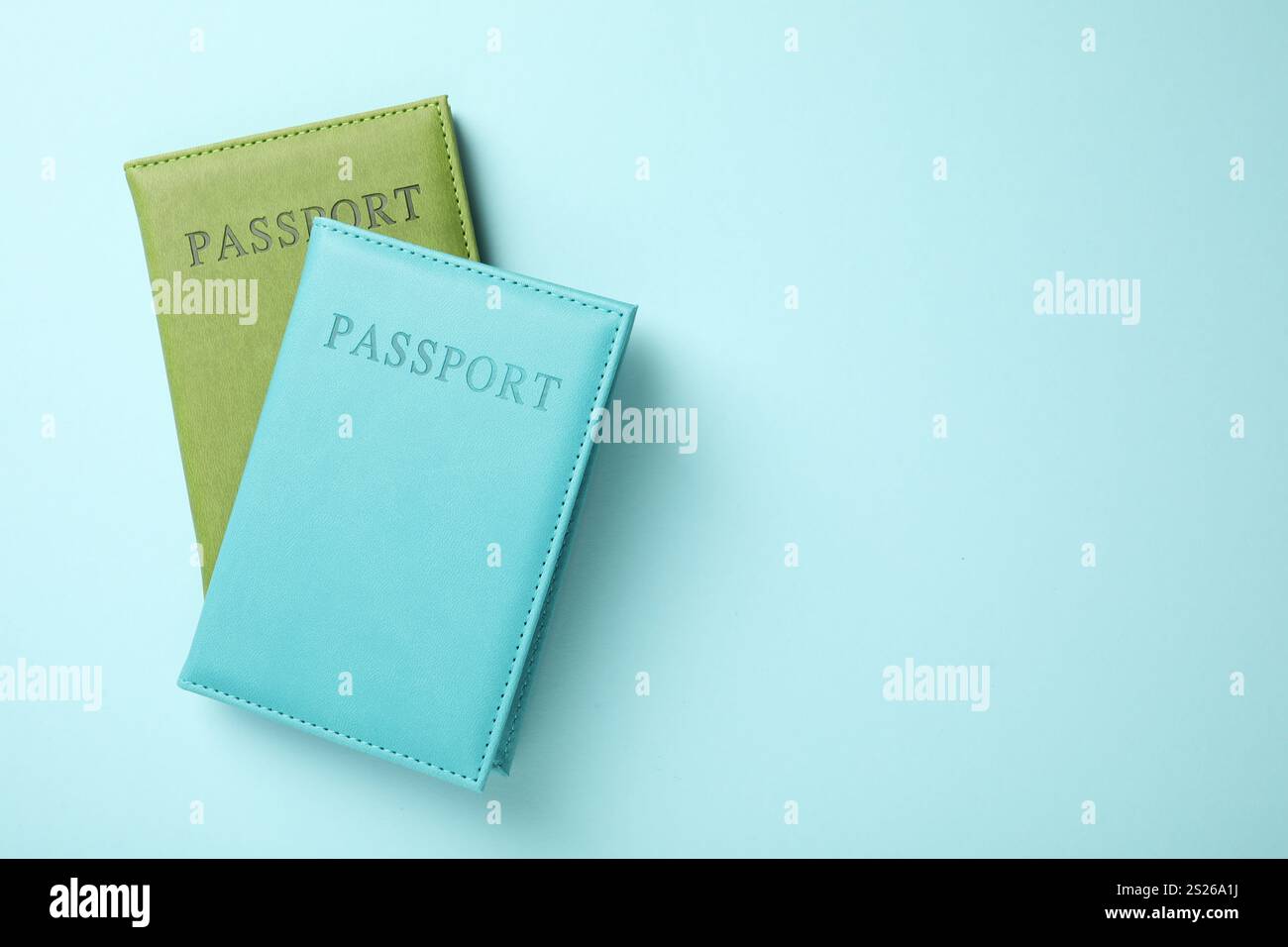Passports in color covers on light blue background, top view. Space for ...