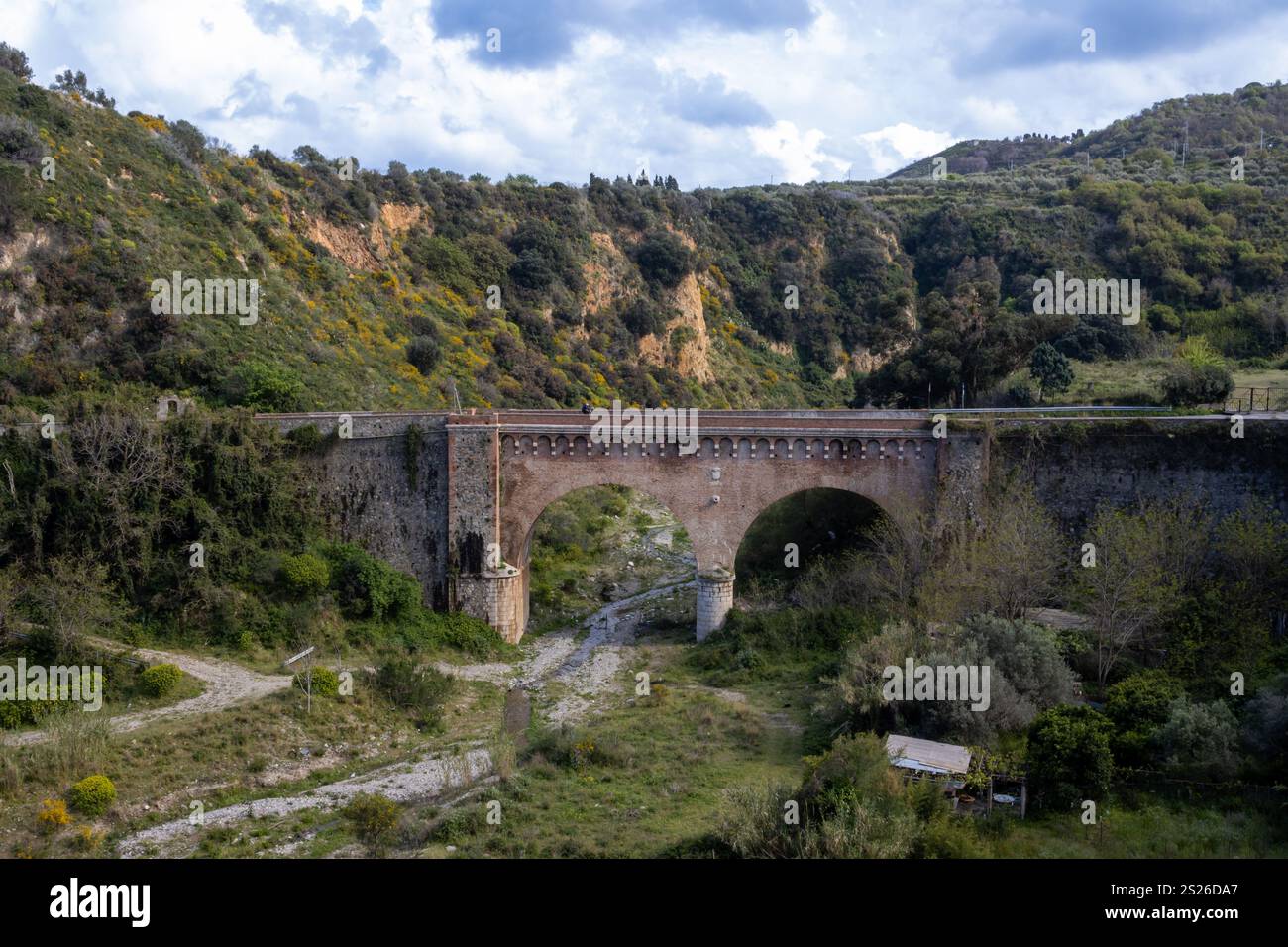 Historical bridge across a dry river, surrounded by forest with trees ...
