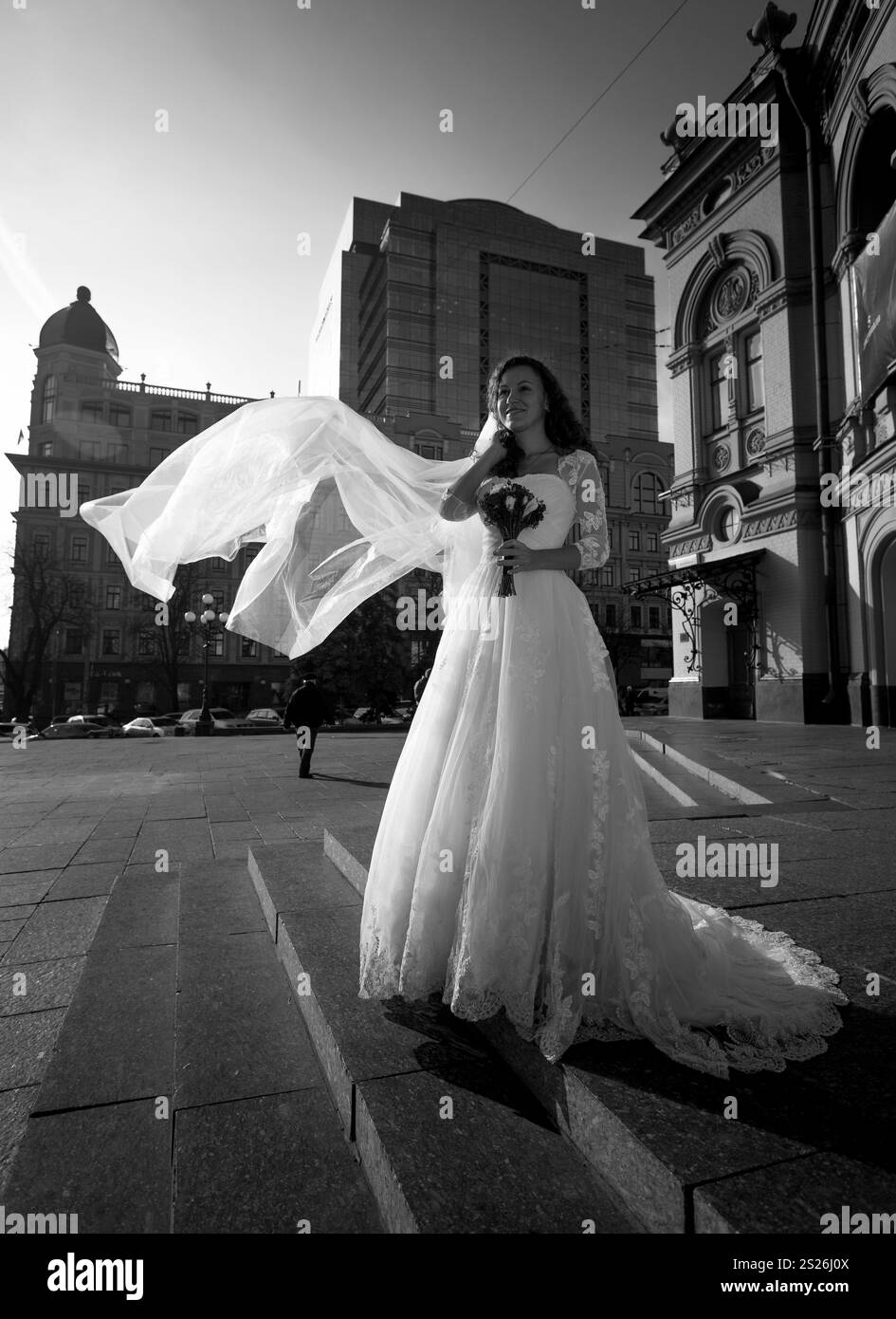 Black and white photo of beautiful bride with long veil posing on old ...
