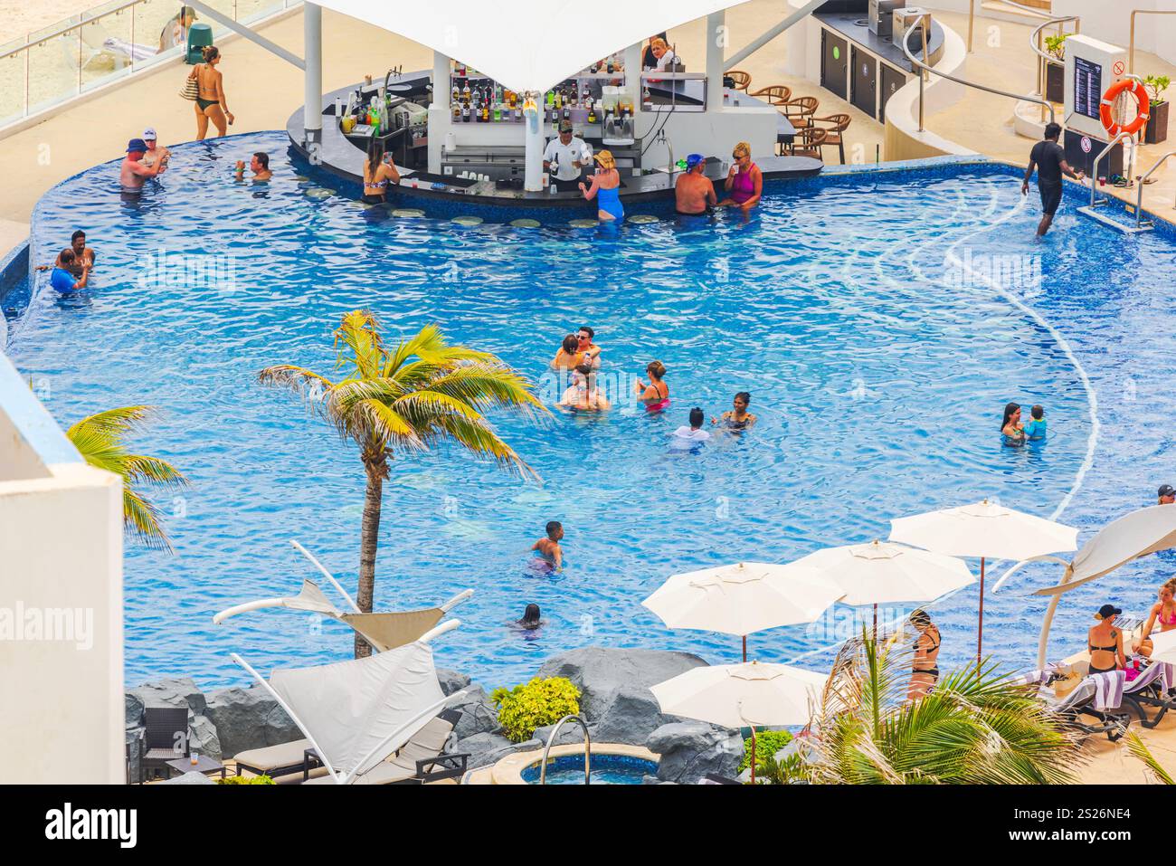Luxury resort swimming pool with swim-up bar, guests enjoying drinks ...