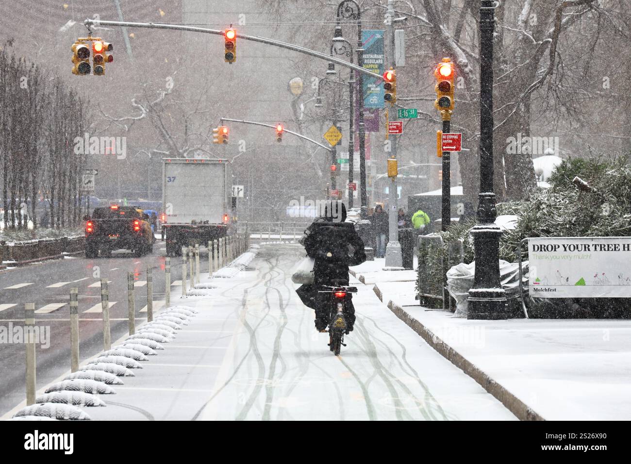 A delivery person rides bike near Union Square Park as snow falls ...