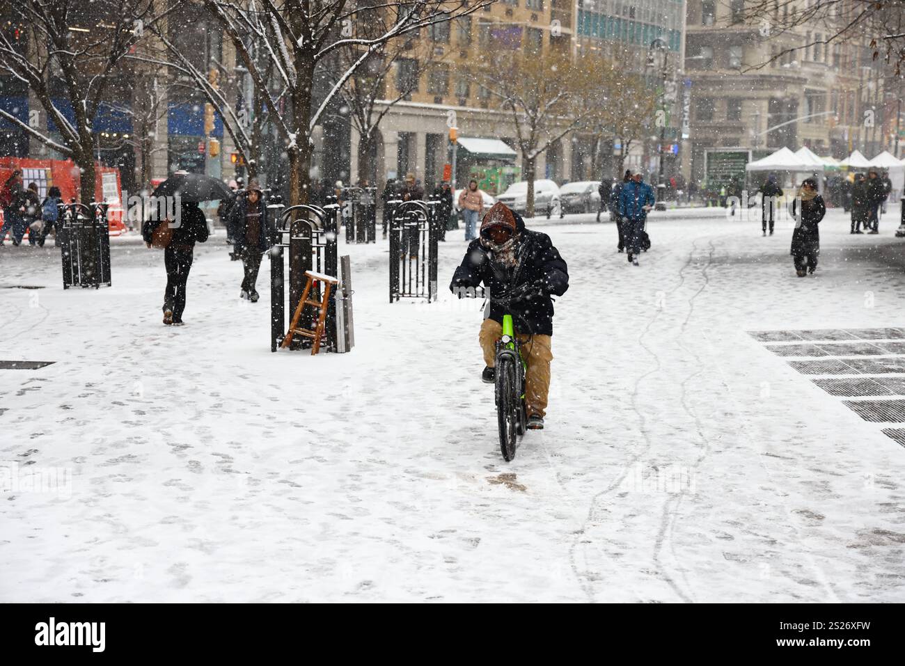 A delivery person rides his bike through in Union Square Park as snow ...