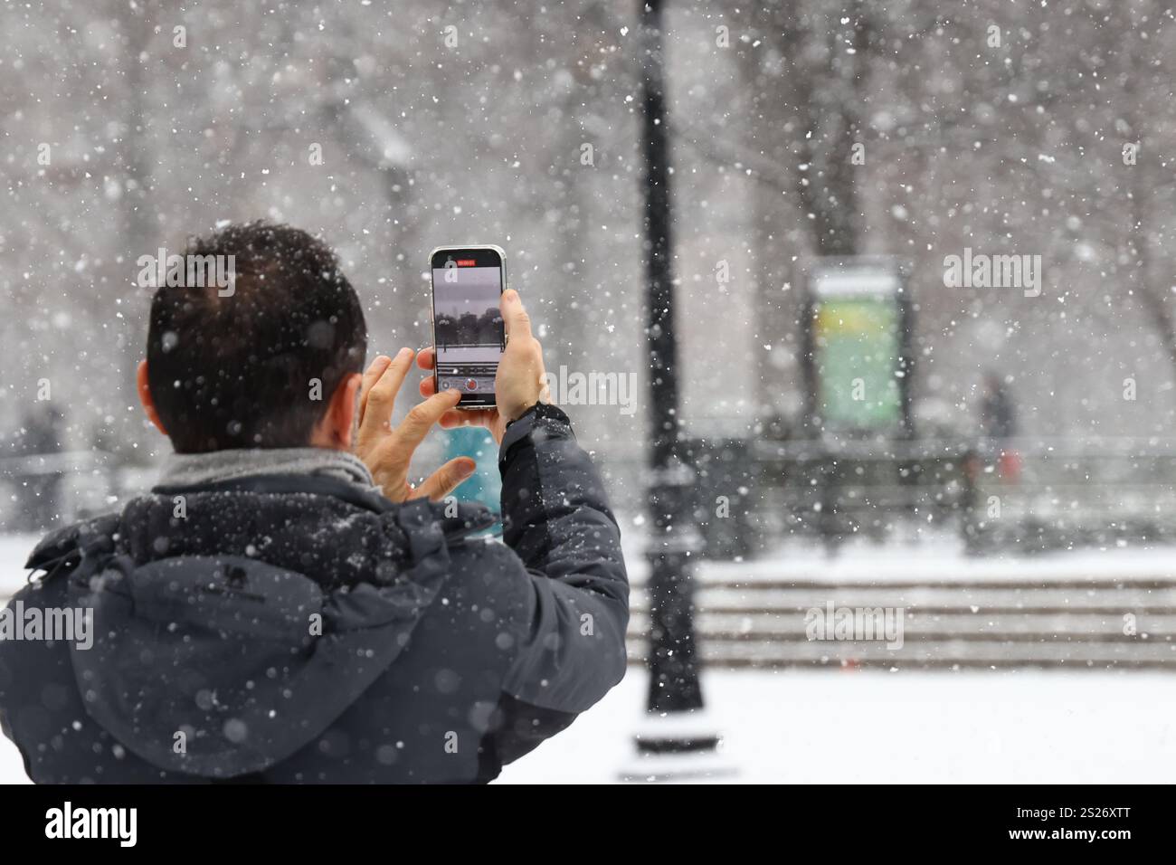 A man takes a photos= in Union Square Park as snow falls heavily in New ...