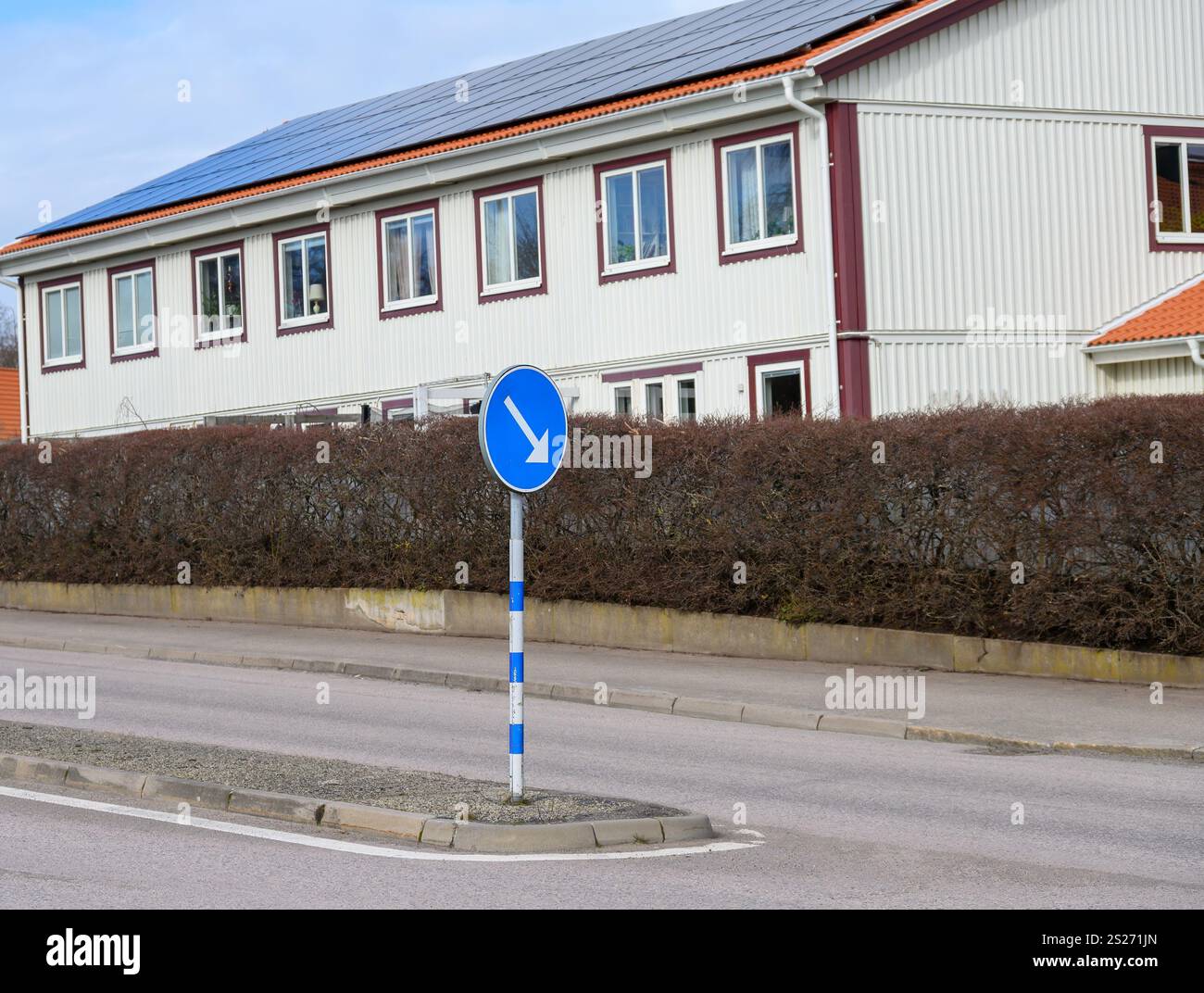A left turn traffic sign stands on a quiet street in a residential ...