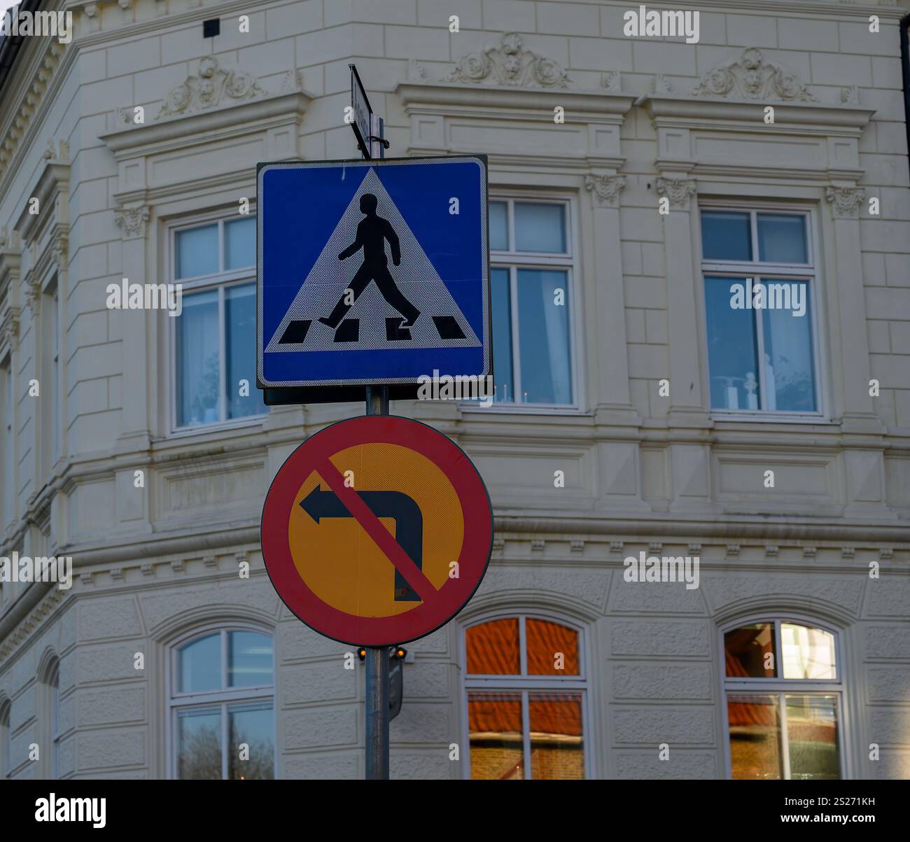 Two traffic signs stand prominently at a street corner, one signaling a ...