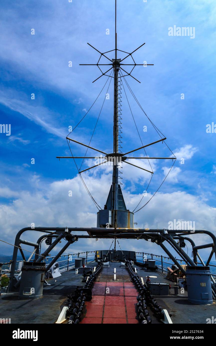 A ship's mast is lit up with lights. The sky is blue and there are ...