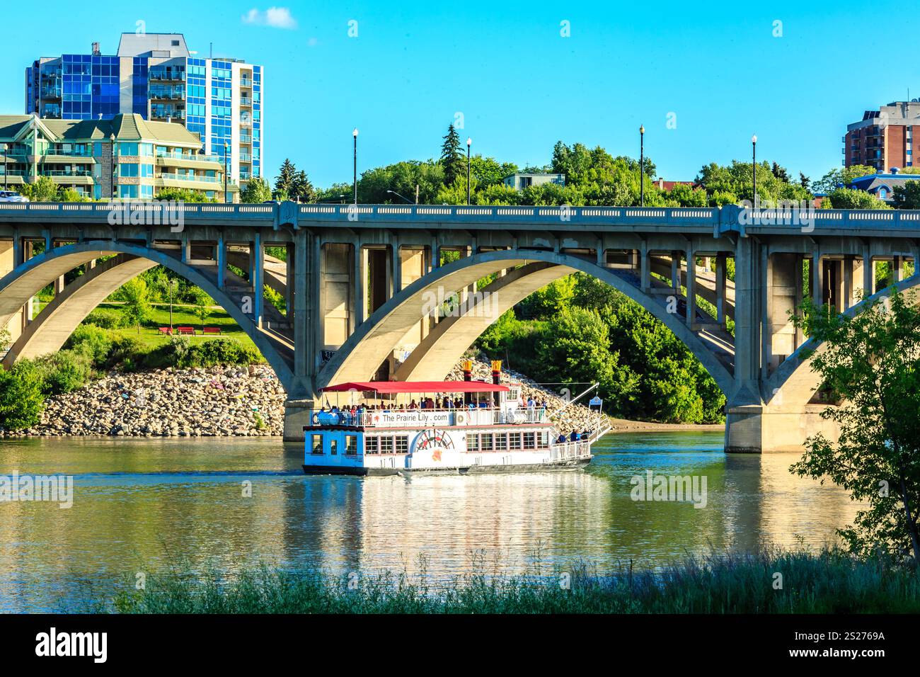 A large white boat with a red top is crossing a bridge. The bridge is ...
