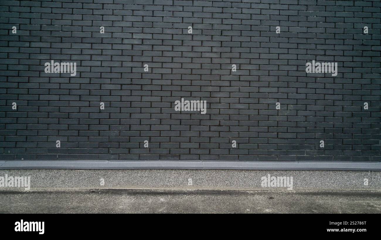 Grungy background with black brick wall and concrete ground. Place for ...