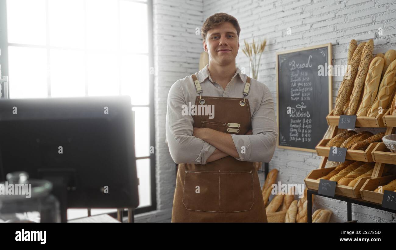 Young man standing confidently in a bakery interior, posing with arms ...