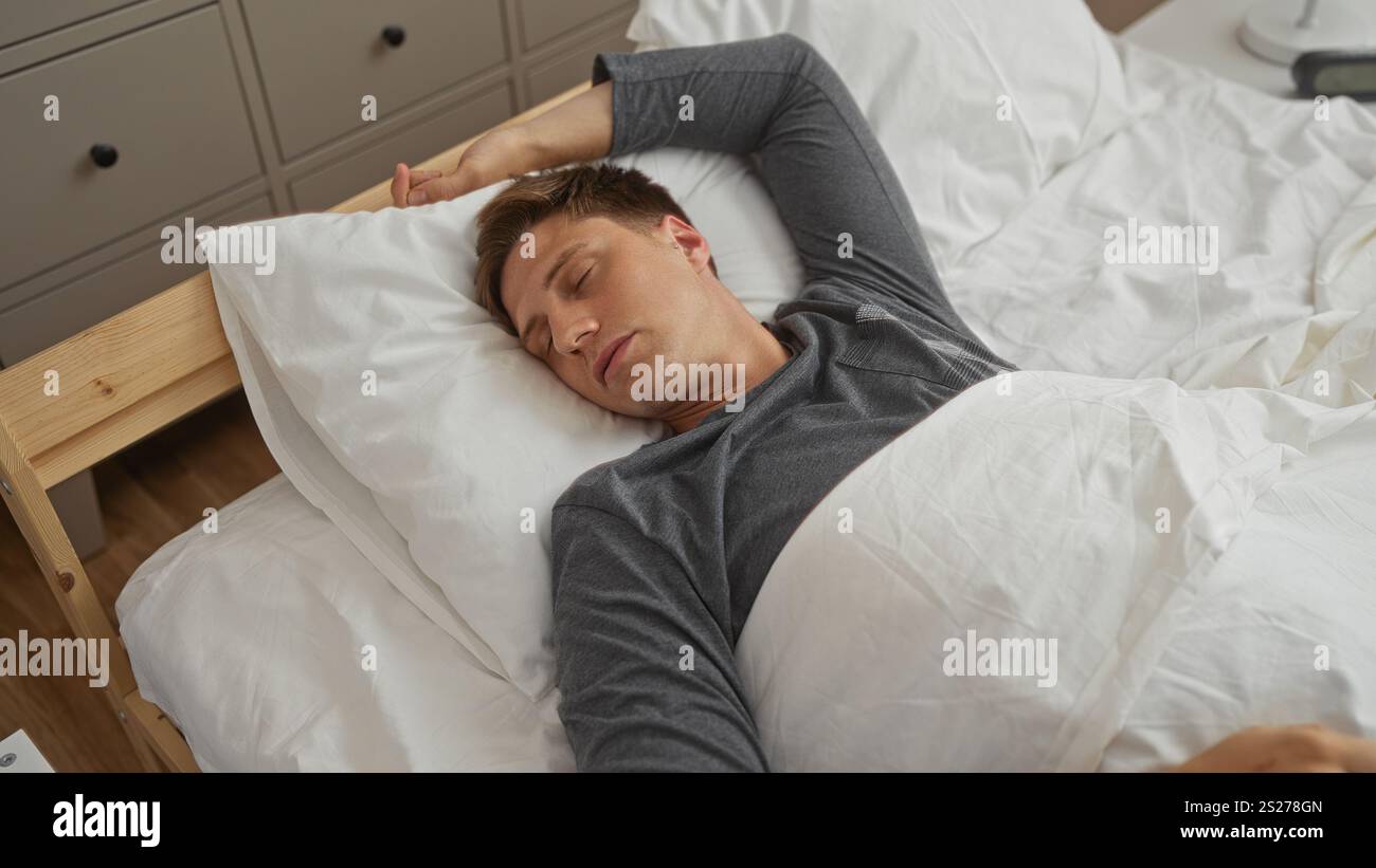 Young man sleeping peacefully in bed with white sheets over isolated ...