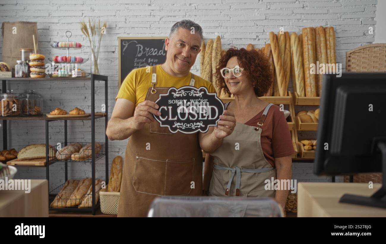 Man and woman bakers holding a closed sign in a bakery shop with ...