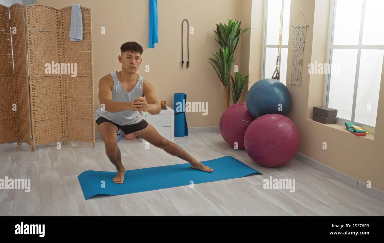 Young chinese man exercising indoors at a wellness center with fitness ...