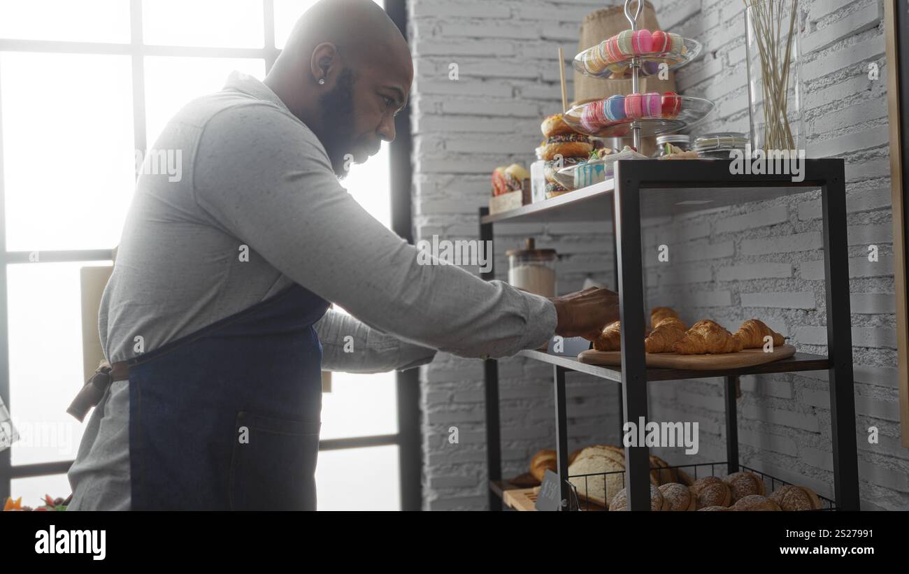 Handsome african american man organizing pastries and macarons in a ...