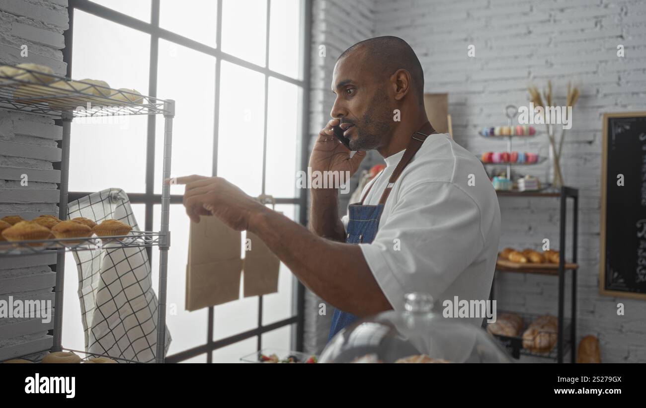 Young man in bakery pointing at shelves while talking on phone ...