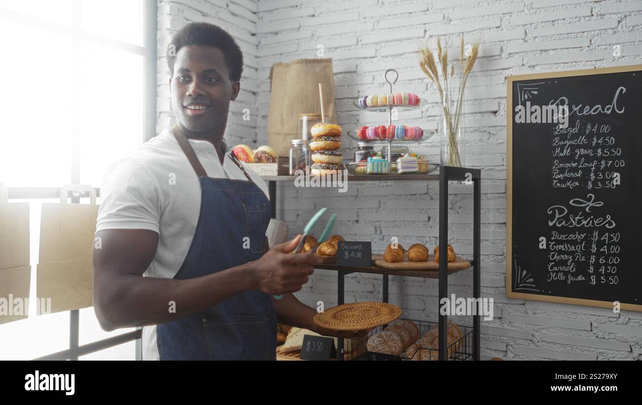 Handsome young man in an apron working in a bakery shop interior with ...