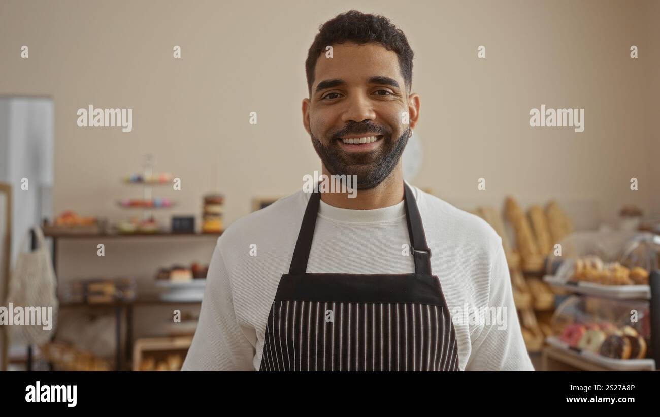 Young hispanic man smiling in a bakery shop interior while wearing a ...