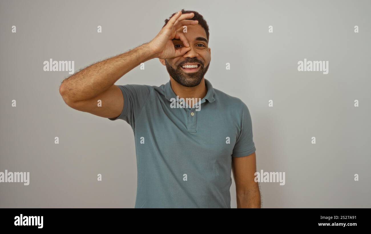 Young man making an ok gesture with his hand over one eye, smiling ...