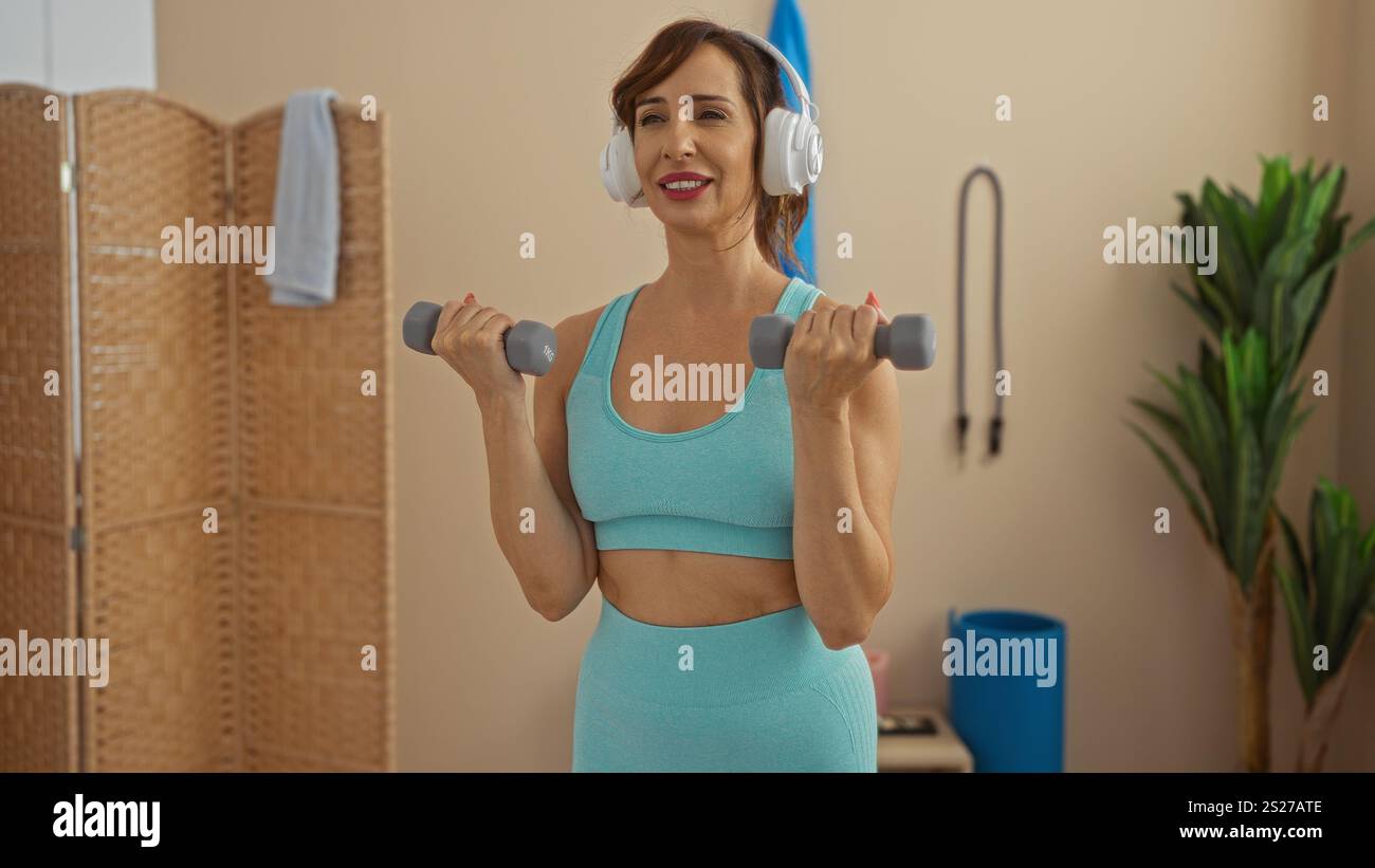 Middle-aged woman exercising with dumbbells at a gym, wearing ...