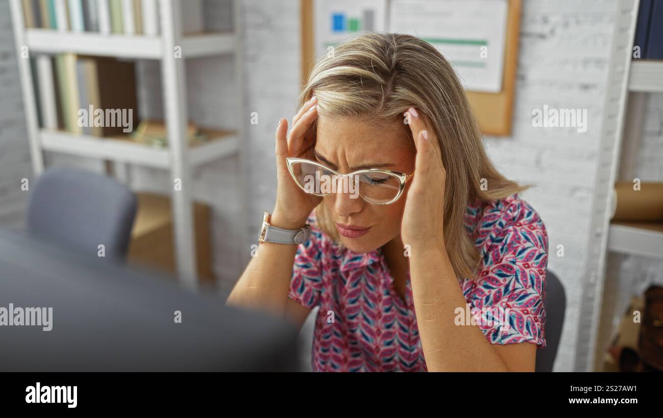Woman stressed at work in a modern office environment with glasses and ...