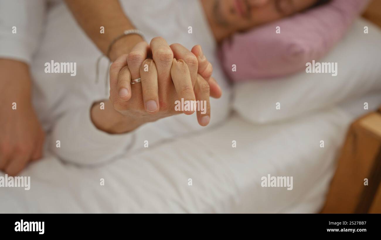 Two men lying together in a bedroom holding hands, symbolizing love and ...