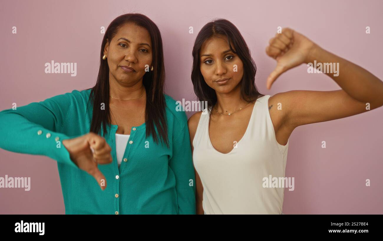 Mother and daughter showing disapproval with thumbs down over a pink ...