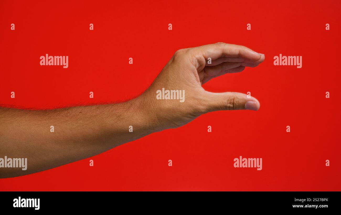 Man holding hand in a gripping gesture against a vibrant red background ...