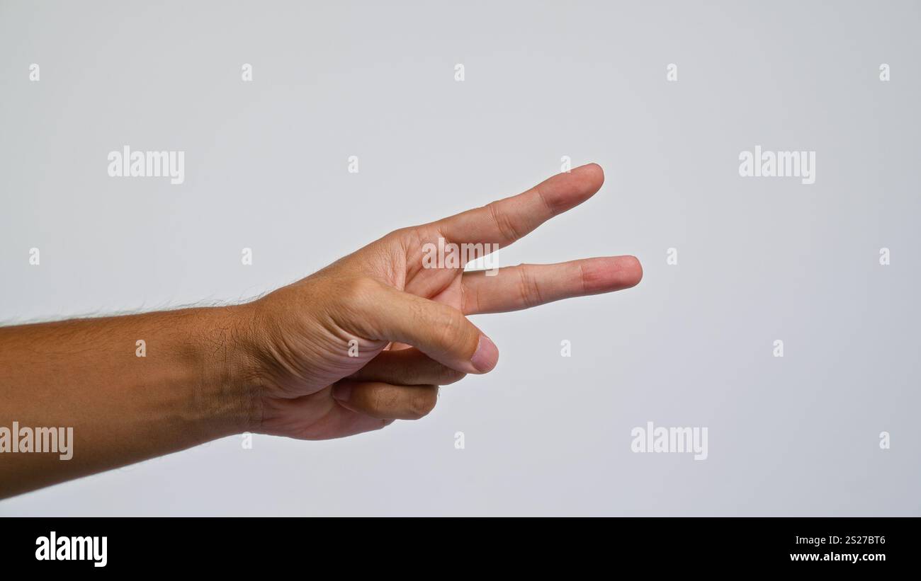 Man's hand showing a peace sign against a plain background symbolizing ...