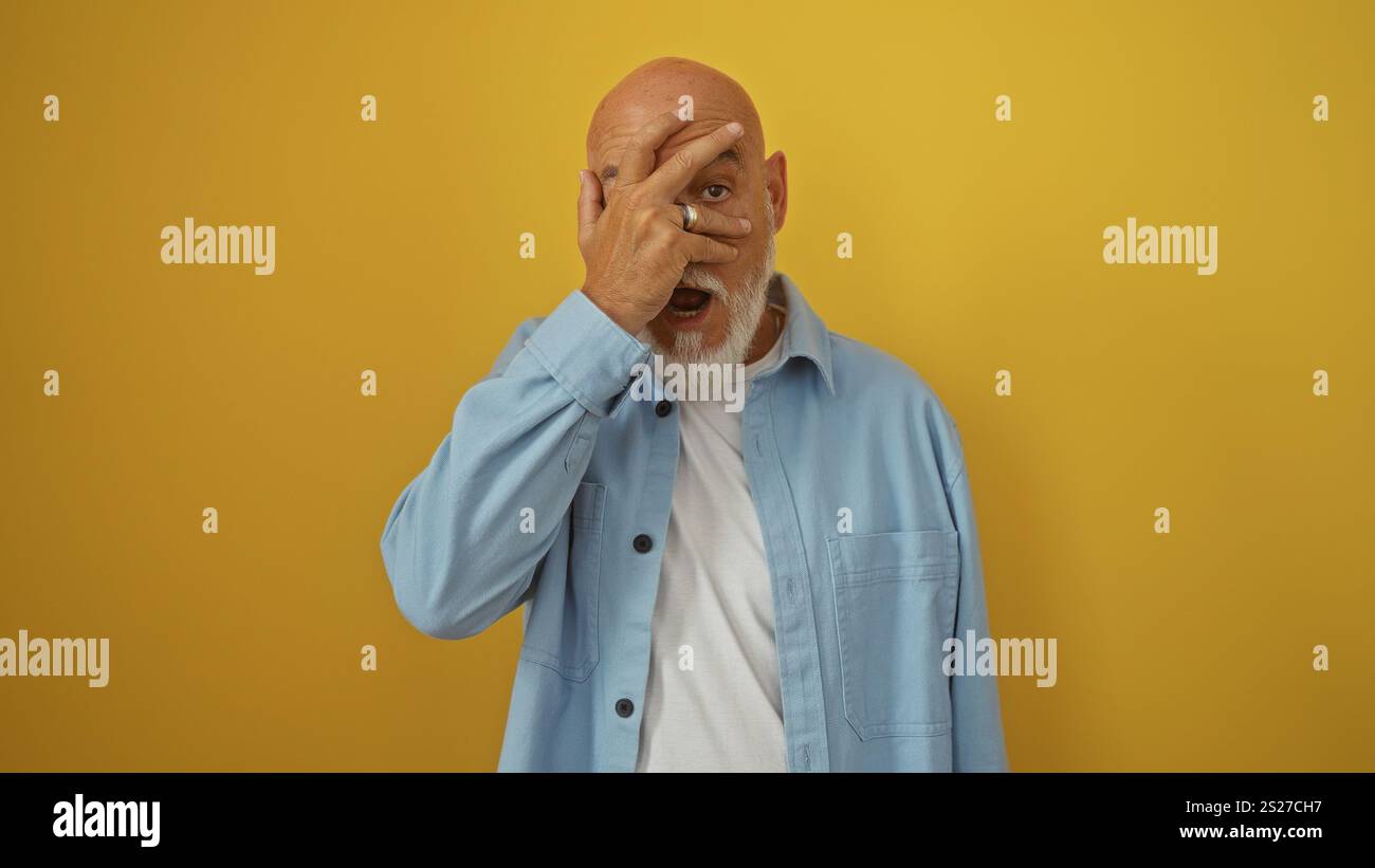 Mature bald man with grey hair and a beard covers his face with his ...