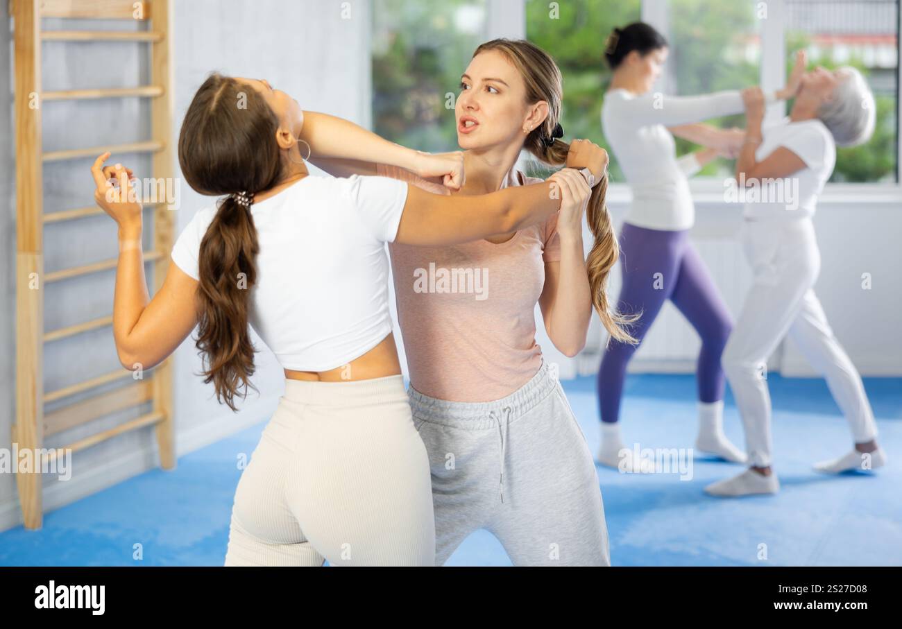 Woman and girl in gym perform basic elements of krav maga self-defense ...