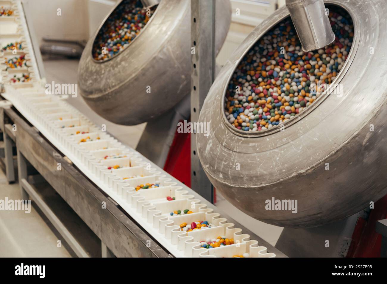 Multi-colored sugar candies spin in a drum at a confectionery ...