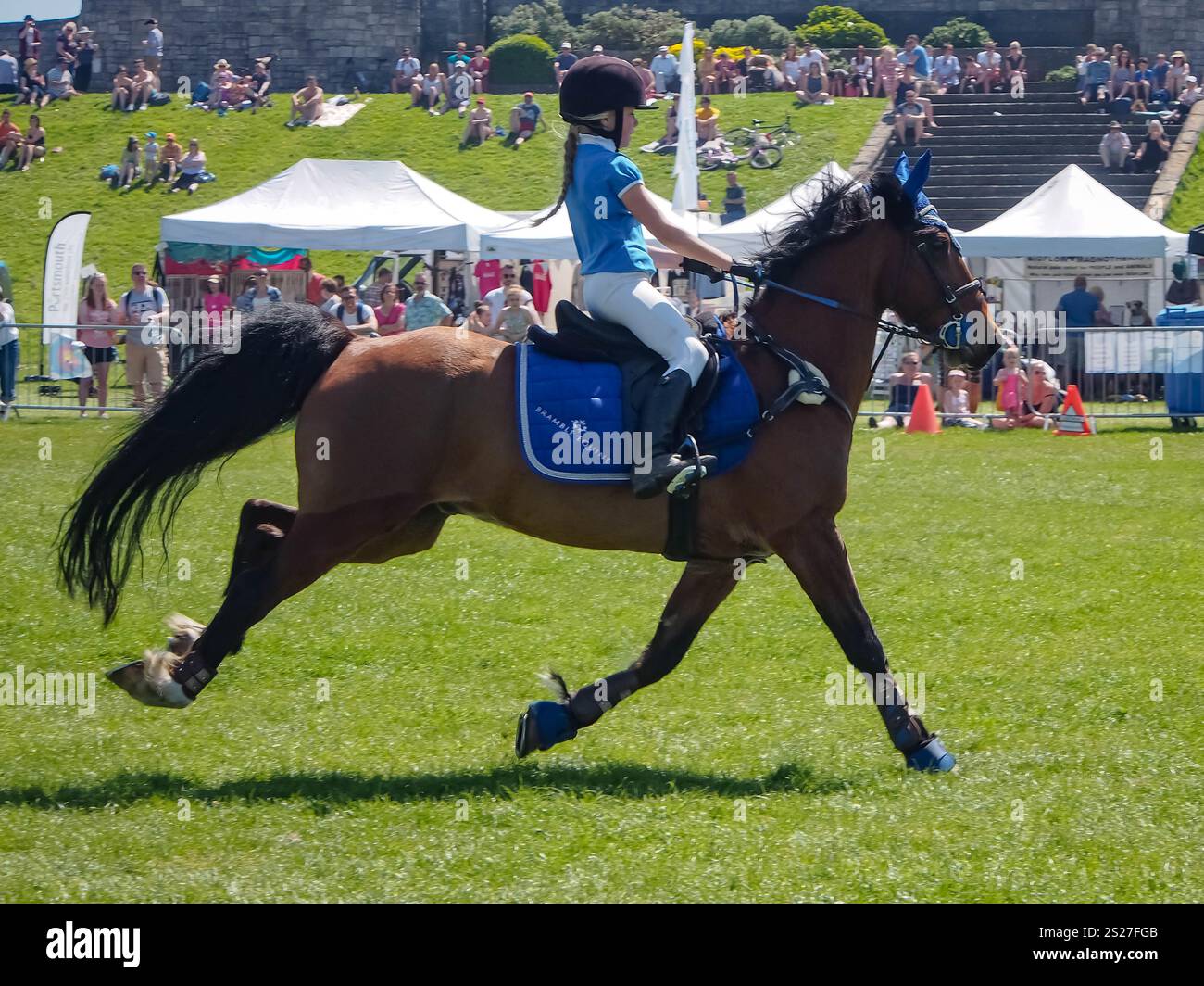 A young girl rides a horse at an equestrian event, watched by ...