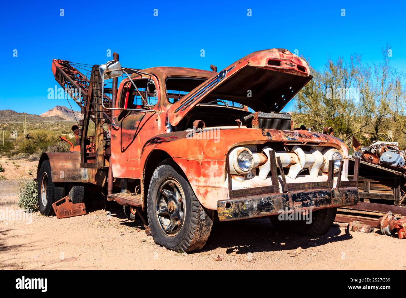 An old rusty truck with a broken hood is parked in the desert. The ...