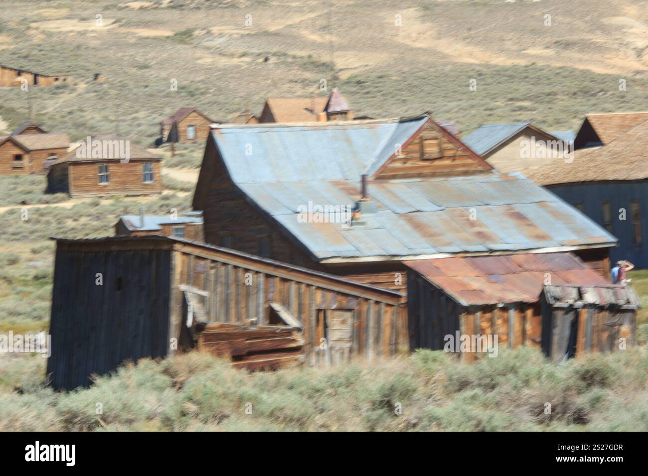 A small, rustic cabin sits in the middle of a desert. The cabin is ...
