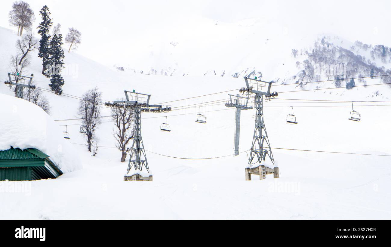 Ski lift towers rise above a thick blanket of snow, surrounded by ...