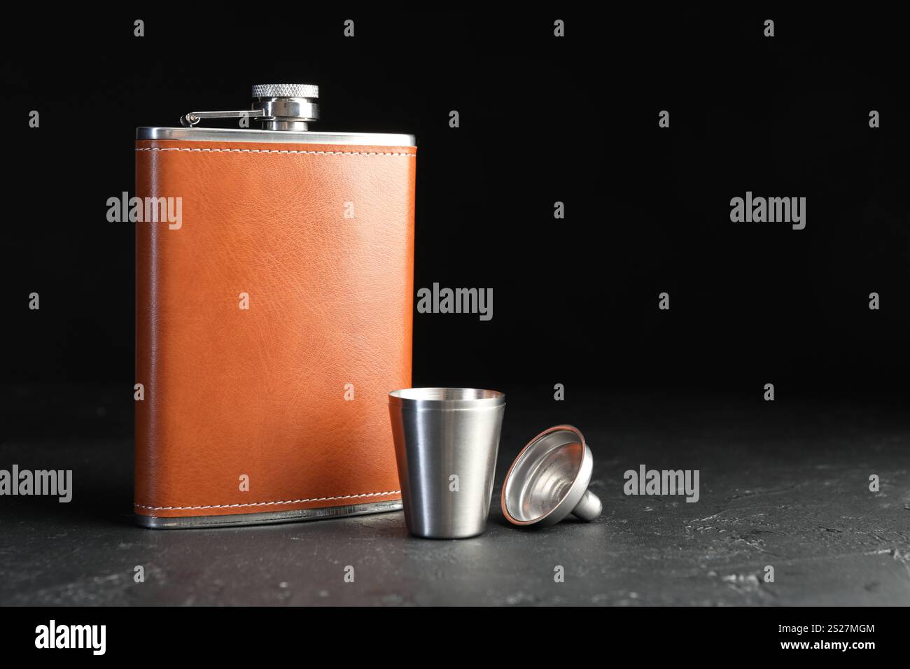 Hip flask, cup and funnel on black table, space for text Stock Photo ...