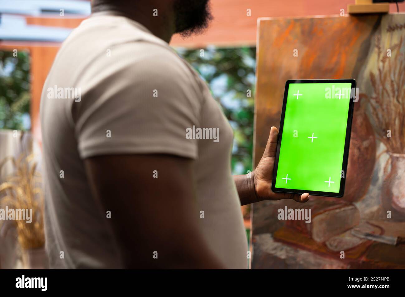 Young artist looking at isolated chroma key display in his painting ...
