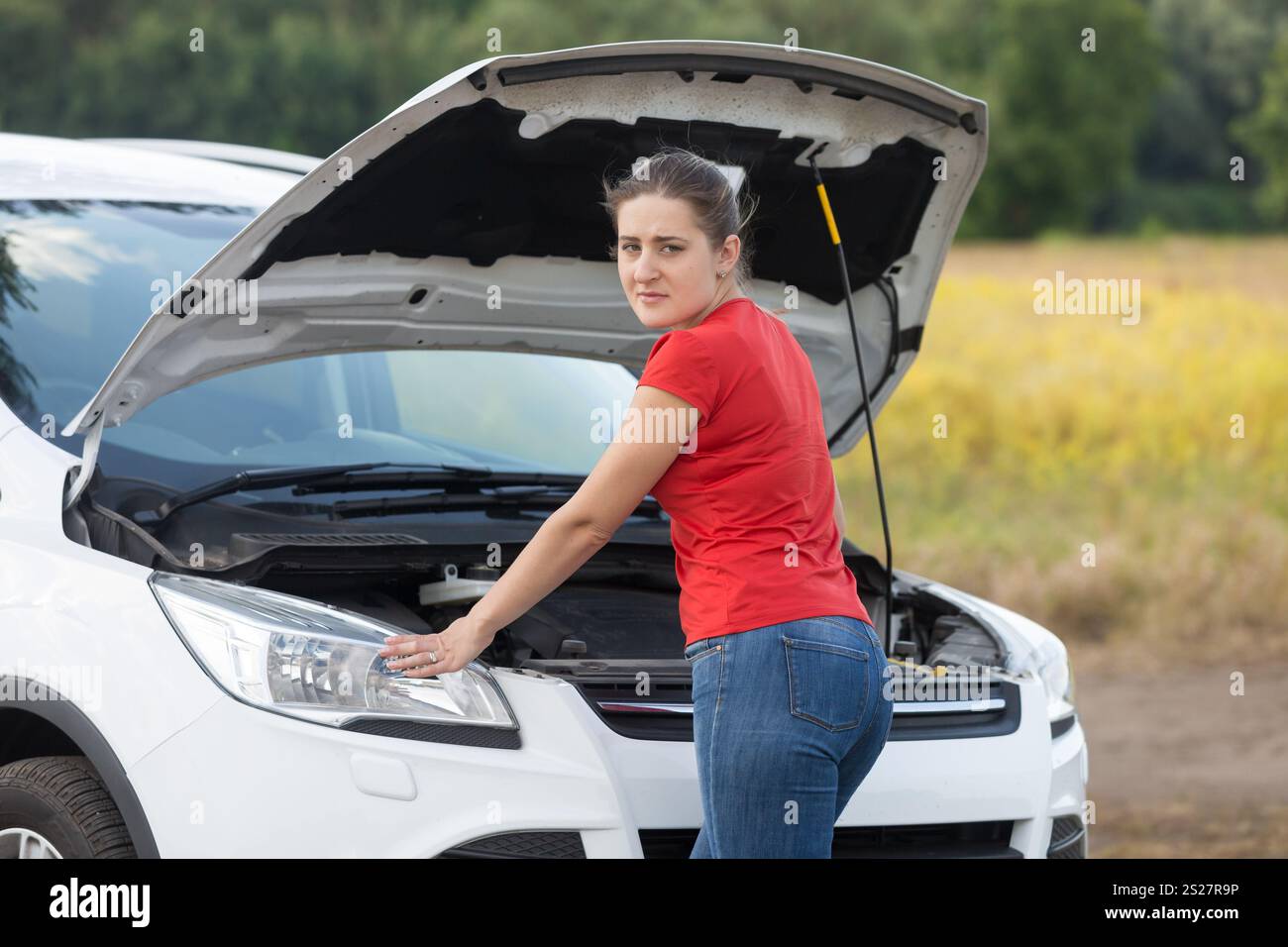 Young woman looking under the hood of broken car at rural road Stock Photo - Alamy