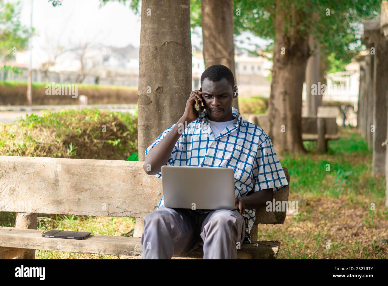 Young cheerful black man using mobile phone and laptop computer. Modern lifestyle Stock Photo ...