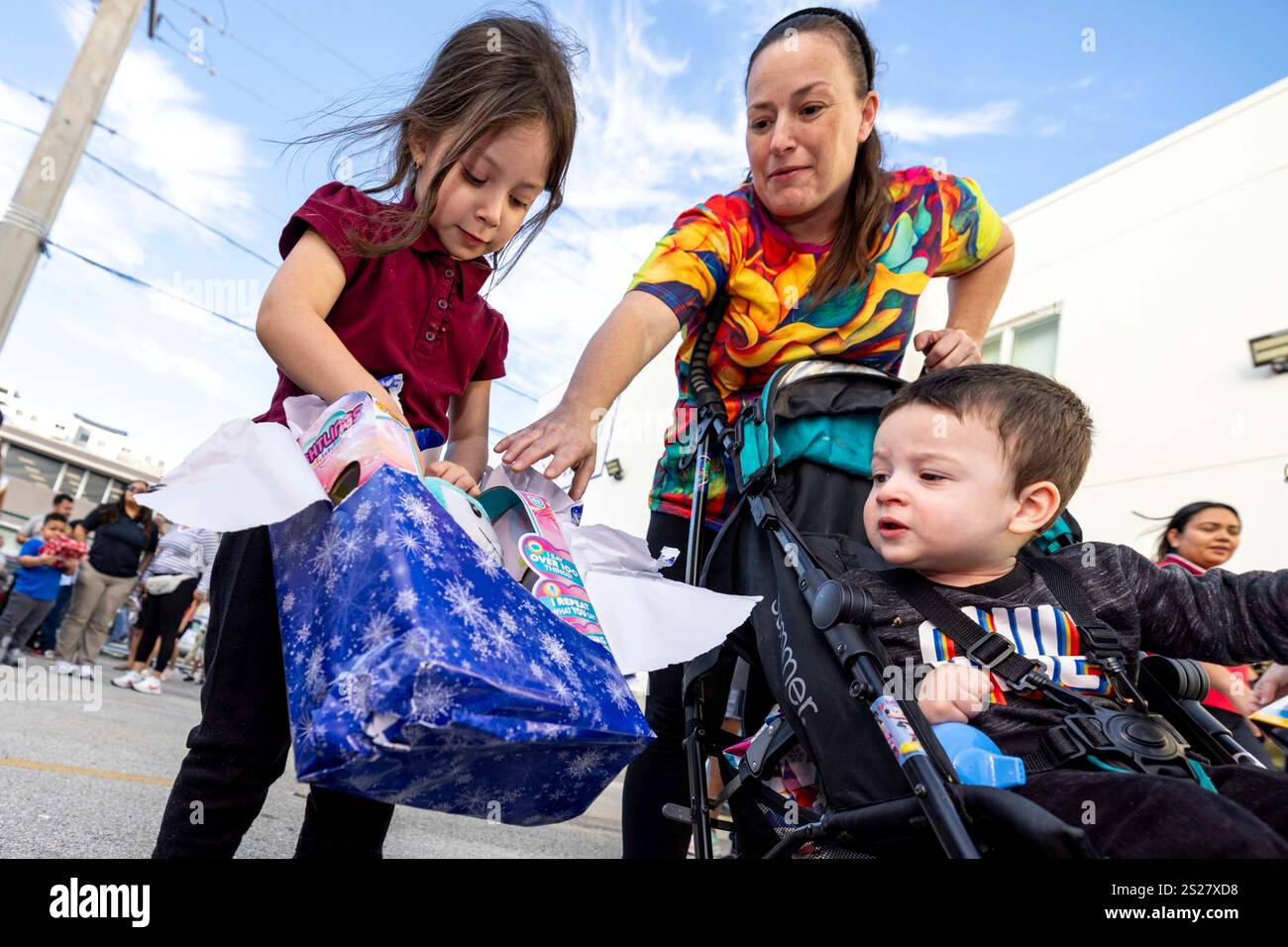 Jada Trabesa, 2, opens a gift as her mother and brother Zeke, 2, look ...