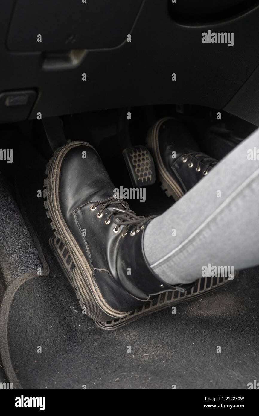 Detail of a person's feet wearing leather boots, while driving a car ...