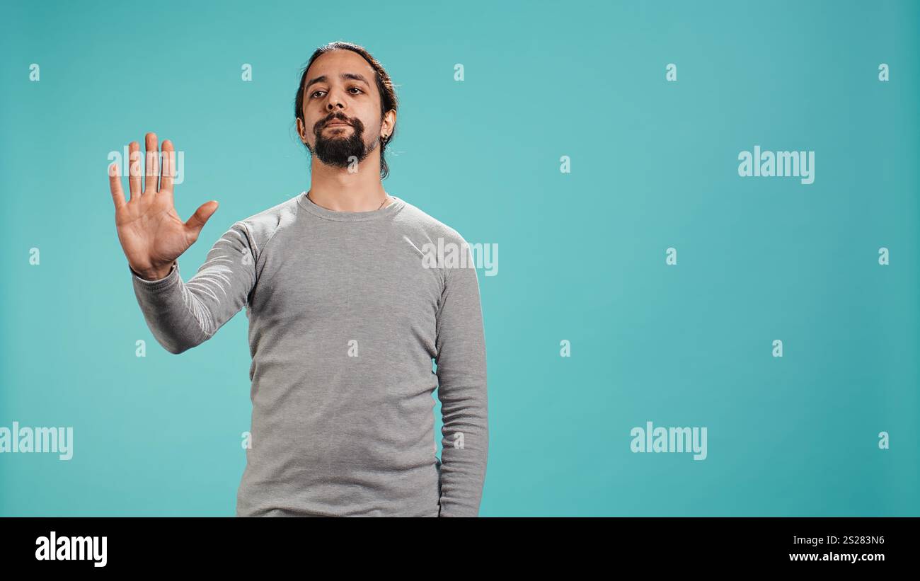 Assertive man doing stop hand gesture sign, studio backdrop. Annoyed ...