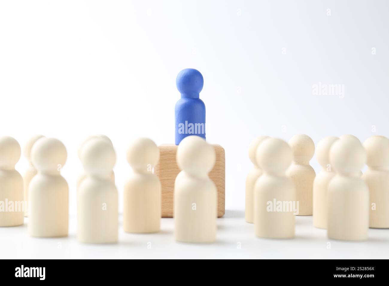 Human figures around wooden block with blue figure on top against white ...
