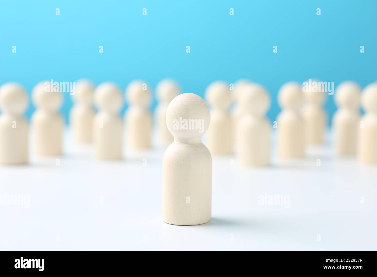 One human figure standing out among others on white table against light ...