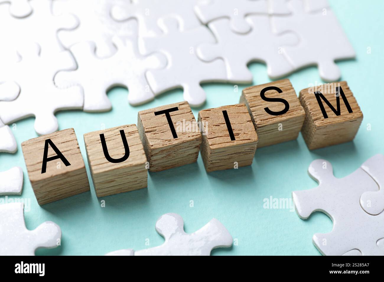 Word Autism made with wooden cubes and puzzle pieces on light blue ...