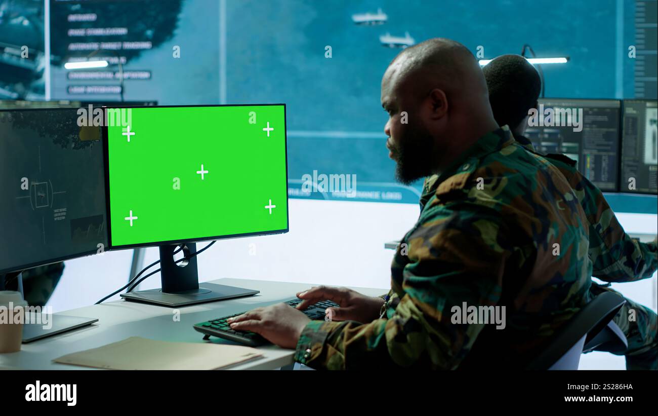 Military specialist monitors satellite data next to green screen ...