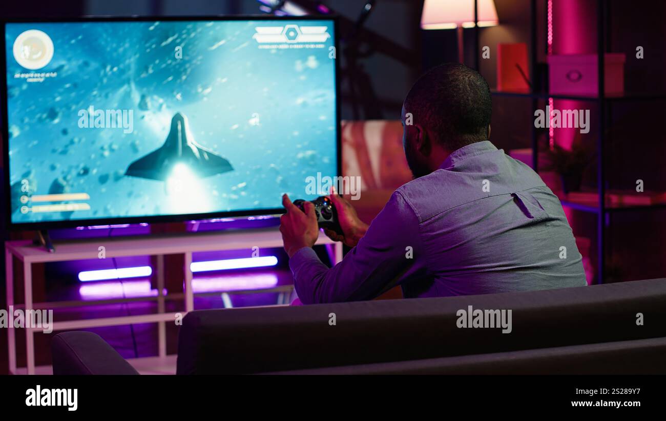 Gamer using controller and headphones to play first person shooter ...